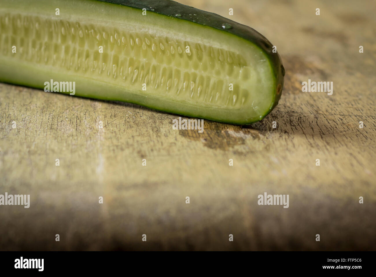 Cucumber sliced lengthwise with seeds on grungy wooden table Stock ...