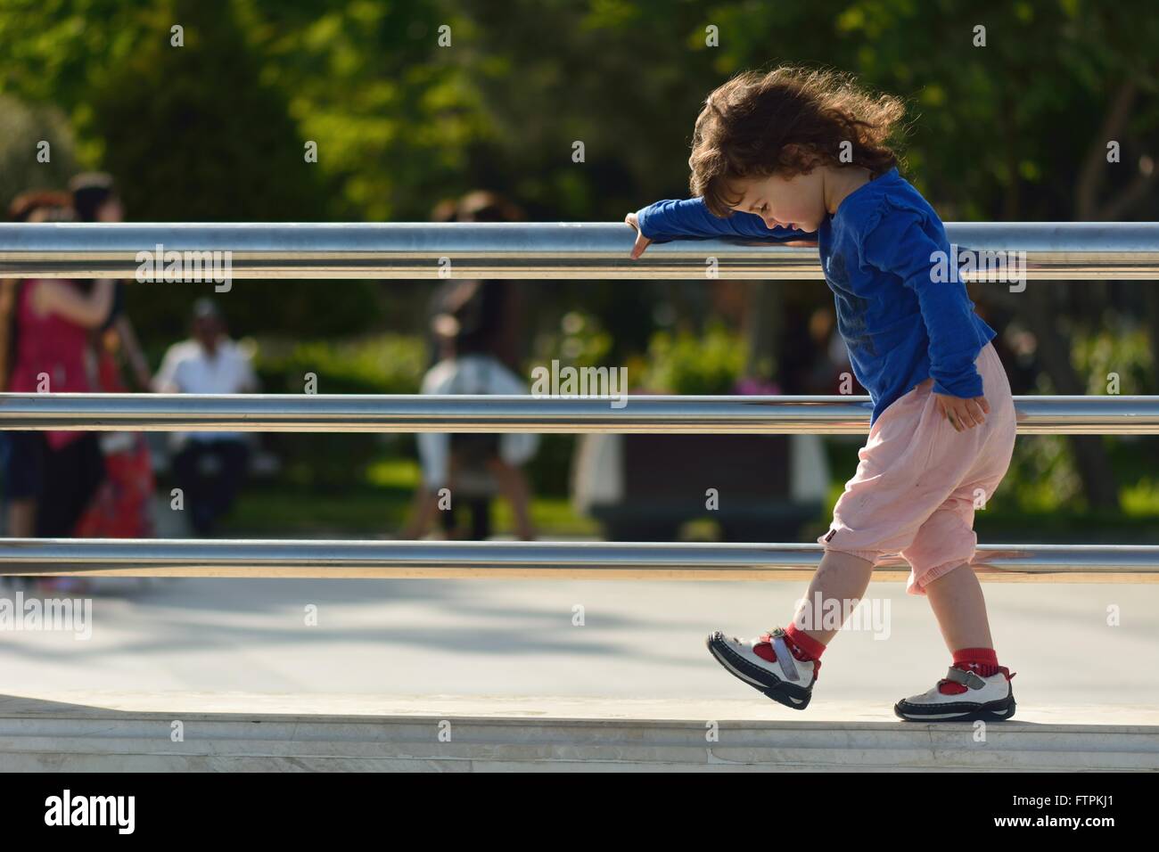 Young girl walking on wall holding metal railings. A small child taking ...