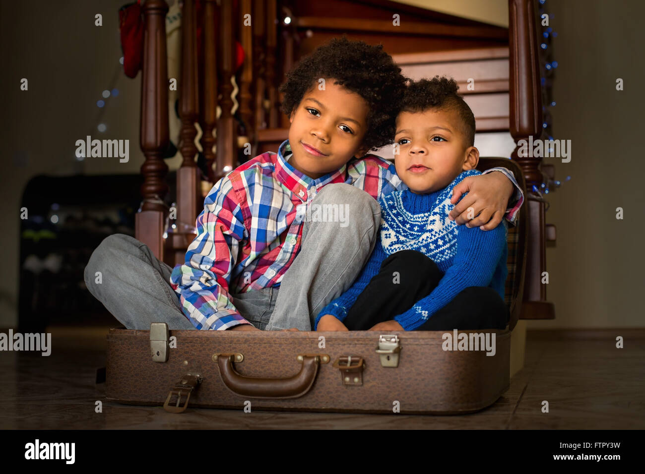 Two boys sitting inside suitcase Stock Photo - Alamy