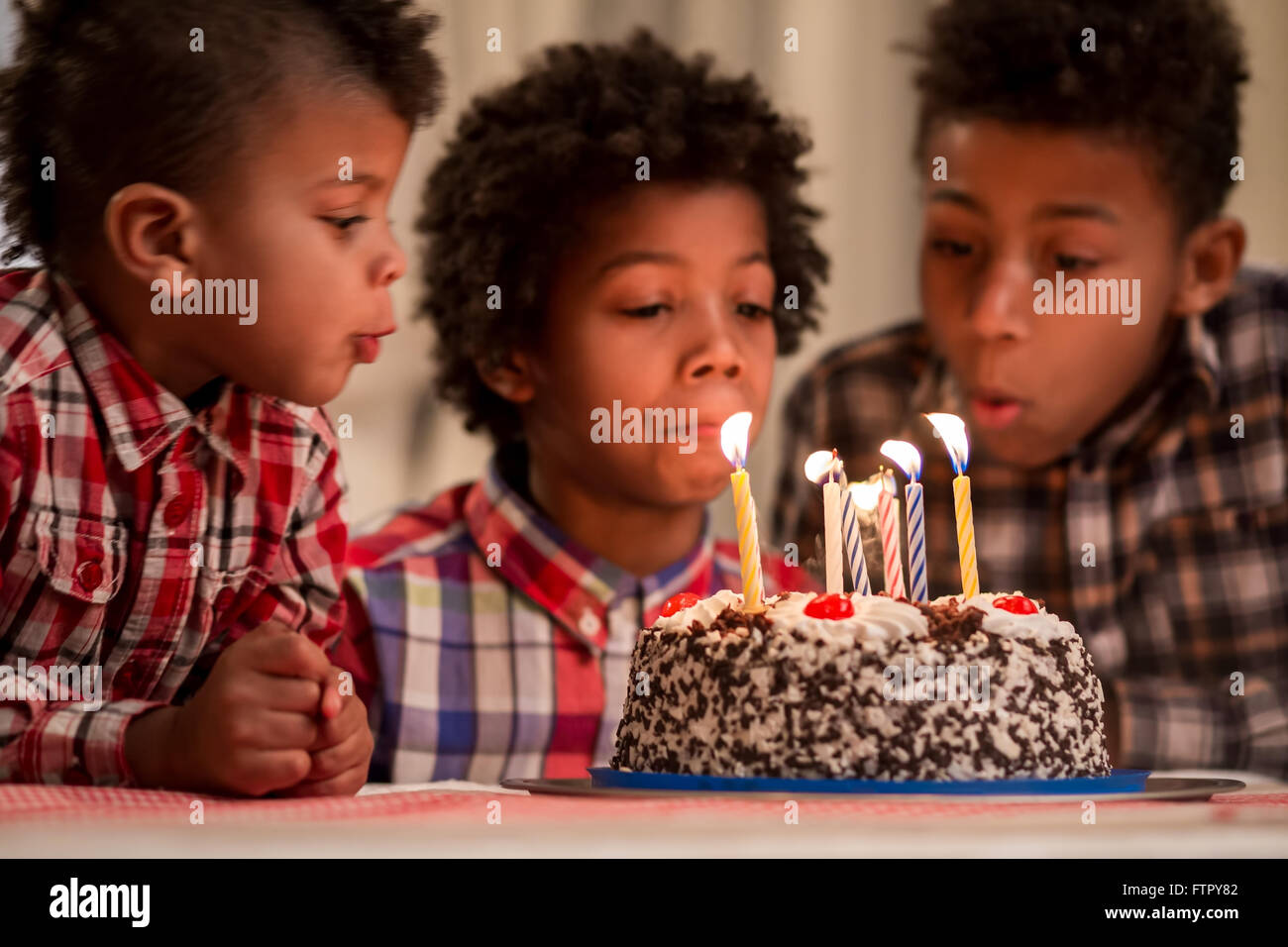 Three kids blowing candles out Stock Photo - Alamy