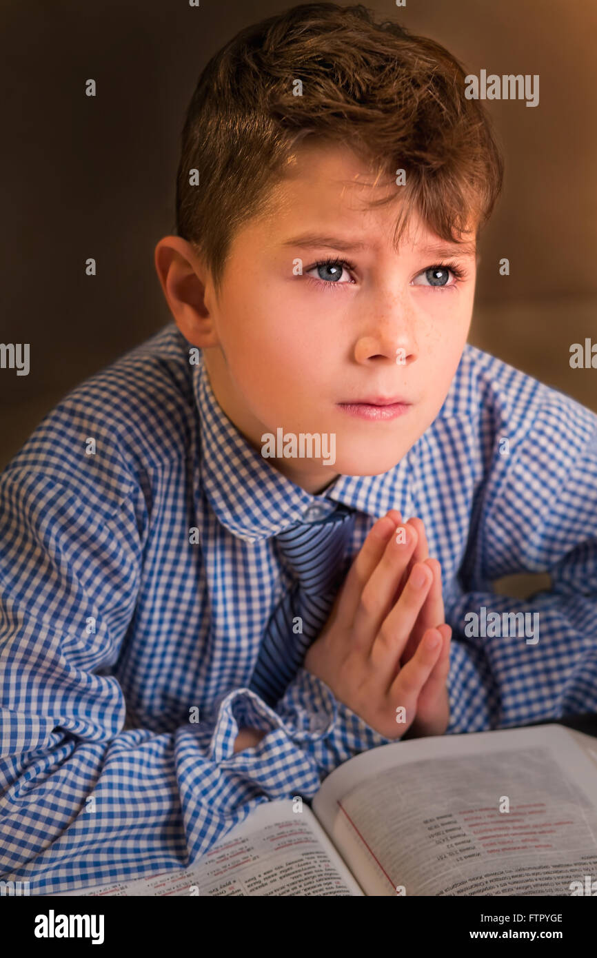 Upset child in shirt praying Stock Photo - Alamy