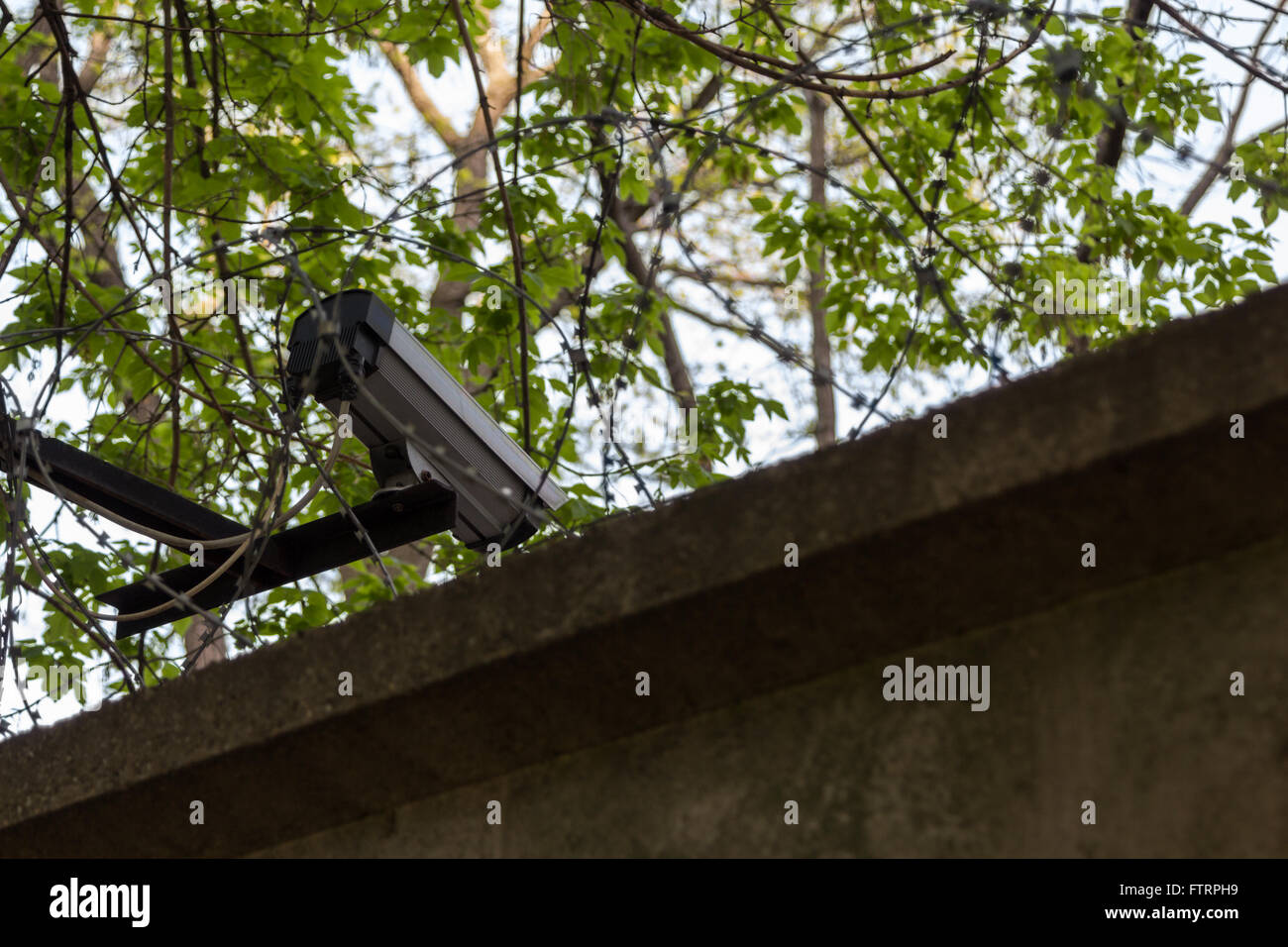 surveillance camera on a concrete fence with barbed wire Stock Photo ...