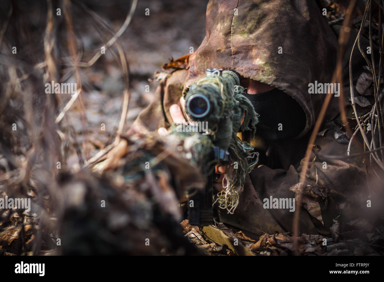 Sniper wearing camouflage suit with rifle hide in the woods Stock Photo ...