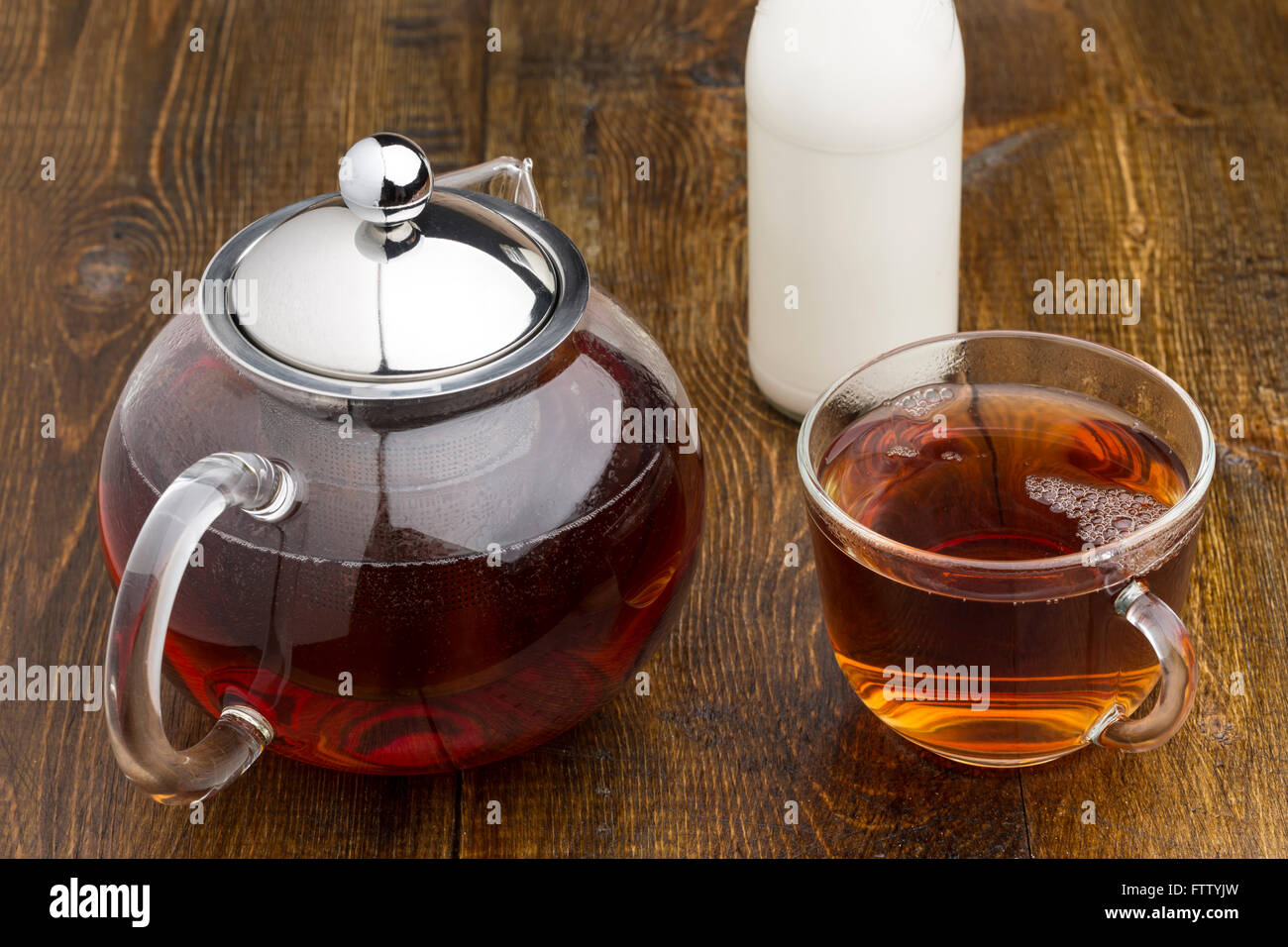 Set of glass teapot, cup and bottle of milk on wooden table Stock Photo ...