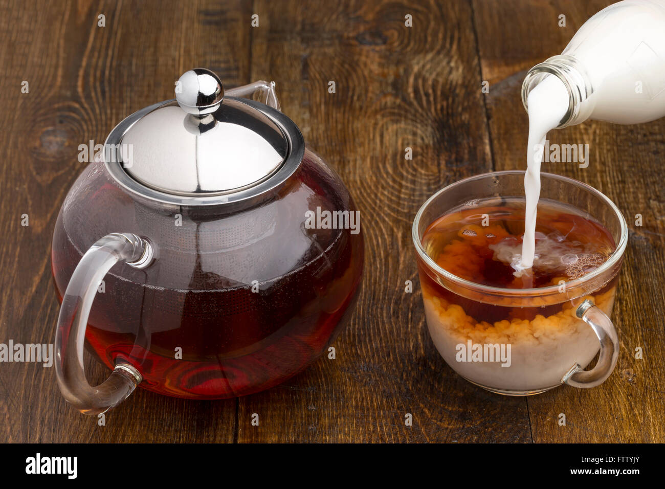 Set of glass teapot, cup and bottle of milk on wooden table Stock Photo ...