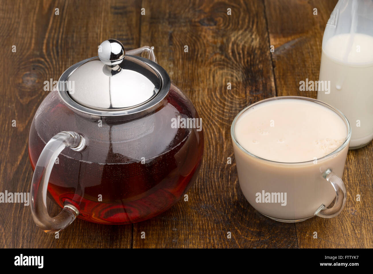 Set of glass teapot, cup and bottle of milk on wooden table Stock Photo ...