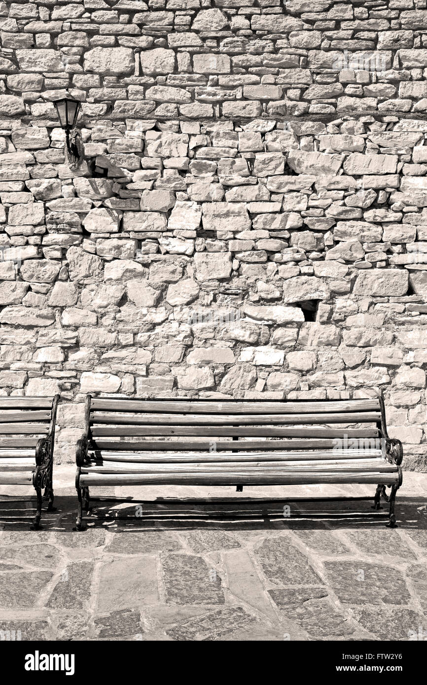 and stone pavement in the greece island of paros old bench near a brick ...