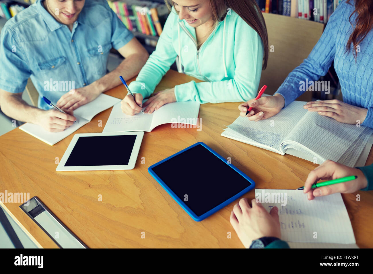 happy students writing to notebooks in library Stock Photo - Alamy