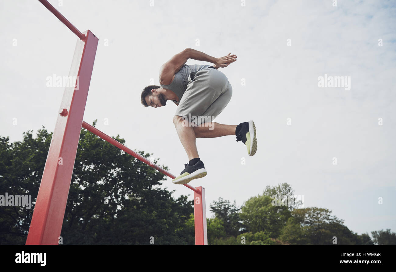 young man jumping on horizontal bar outdoors Stock Photo - Alamy