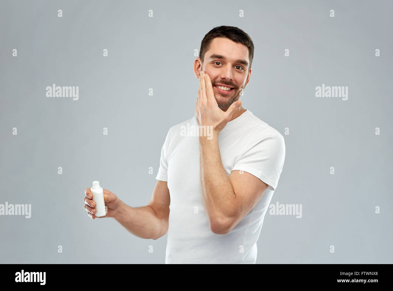 happy young man applying cream or lotion to face Stock Photo - Alamy