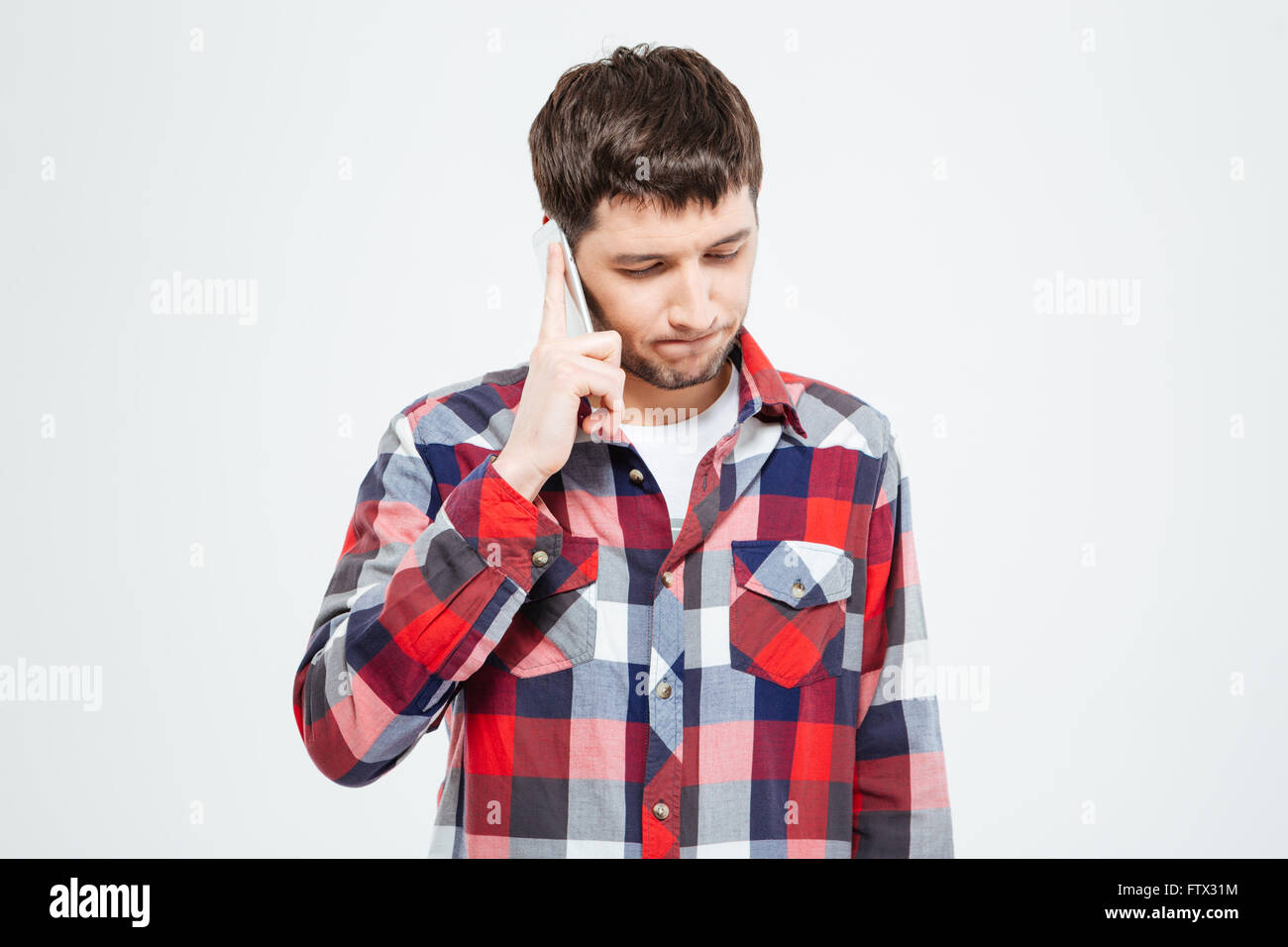Sad casual man talking on the phone isolated on a white background ...