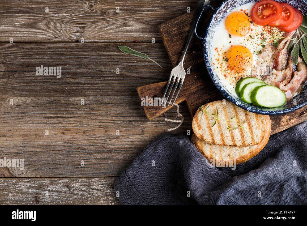 Breakfast set. Pan of fried eggs with bacon, fresh tomato, cucumber ...