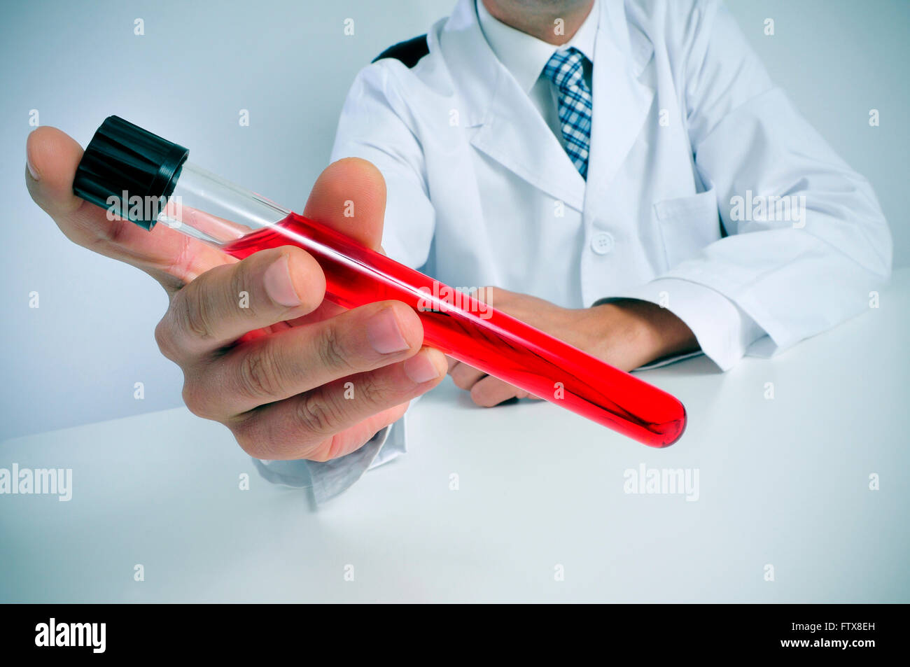 closeup of a young caucasian man wearing white coat sitting at his desk ...