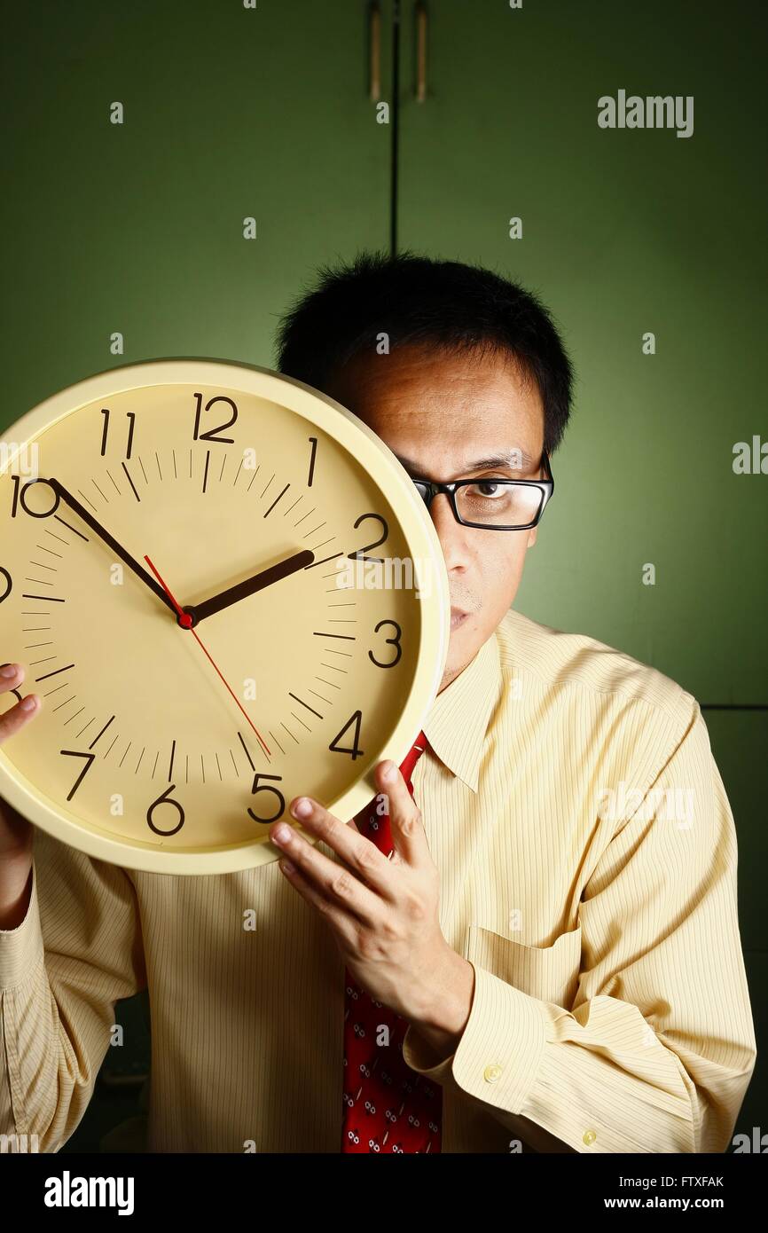 Man holding a clock to his face Stock Photo - Alamy