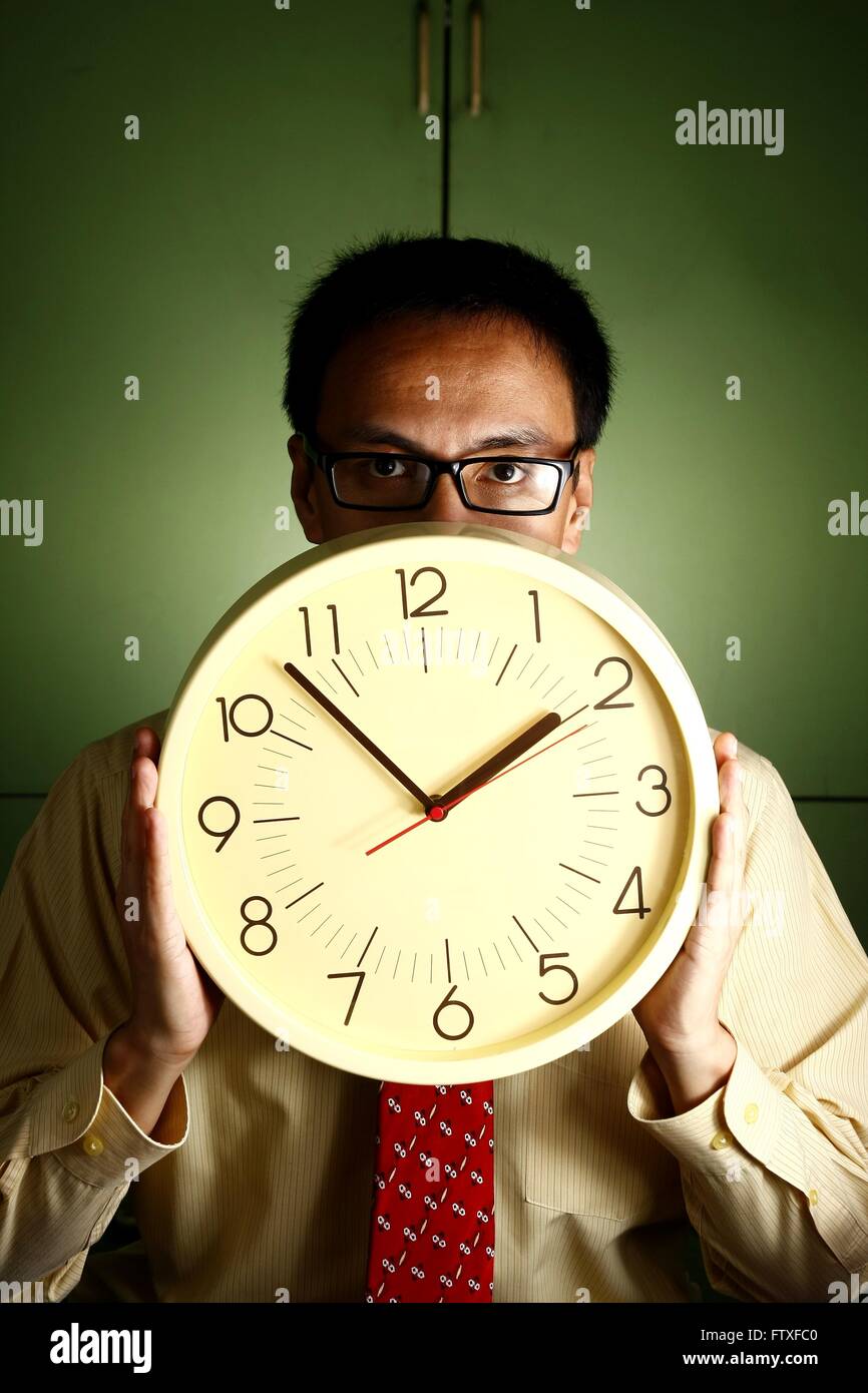 Man holding a clock to his face Stock Photo - Alamy