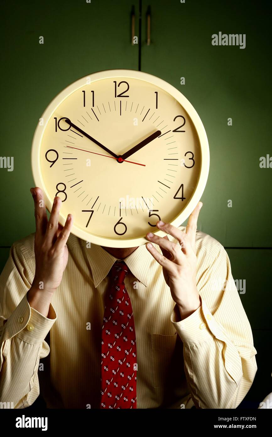 Man holding a clock to his face Stock Photo - Alamy