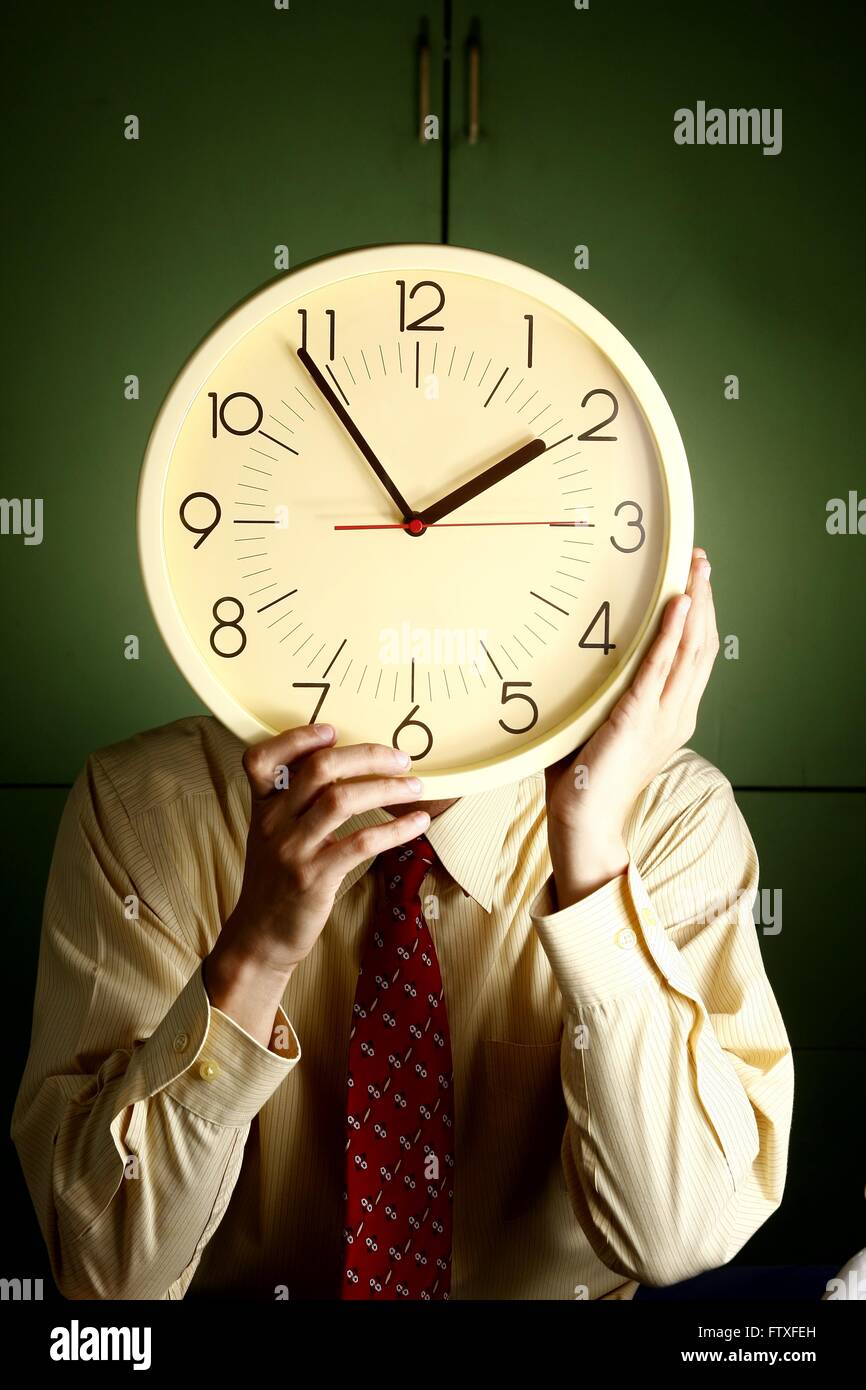 Man holding a clock to his face Stock Photo - Alamy