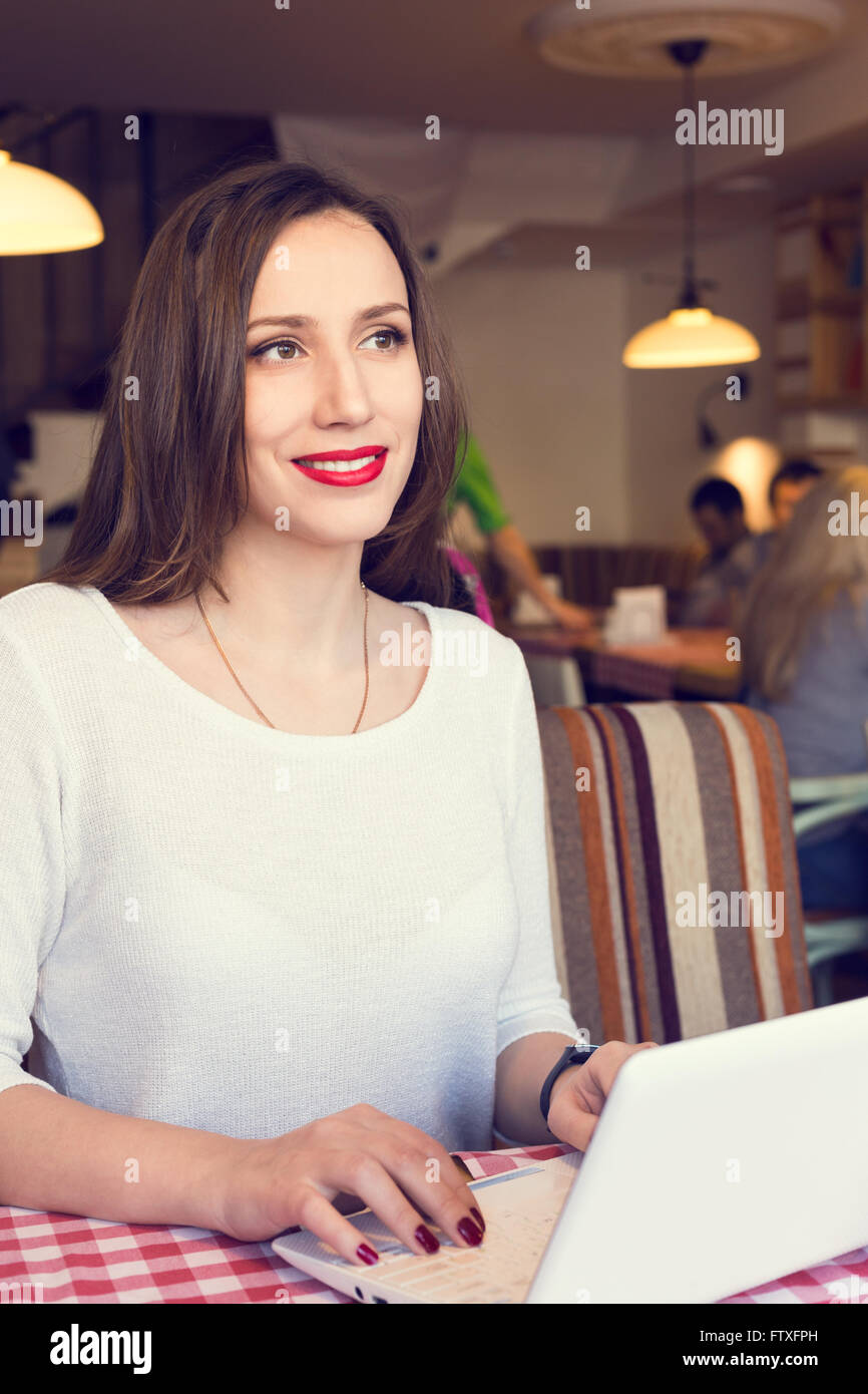 Young happy woman using notebook in cafe. Pretty girl working with ...