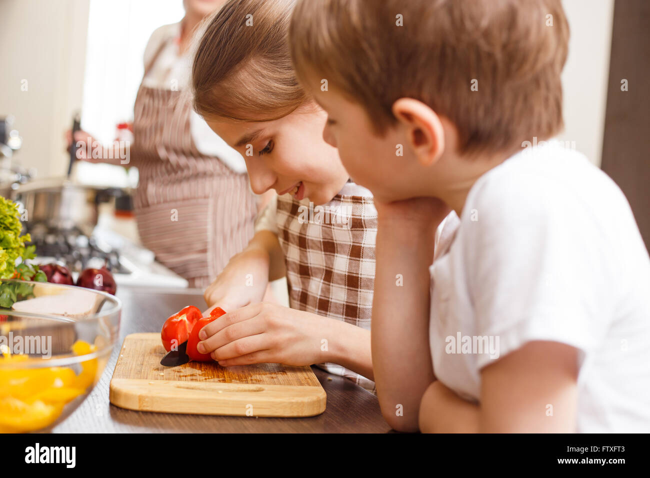 Family cooking background. Sister and brother cutting tomato and mother ...
