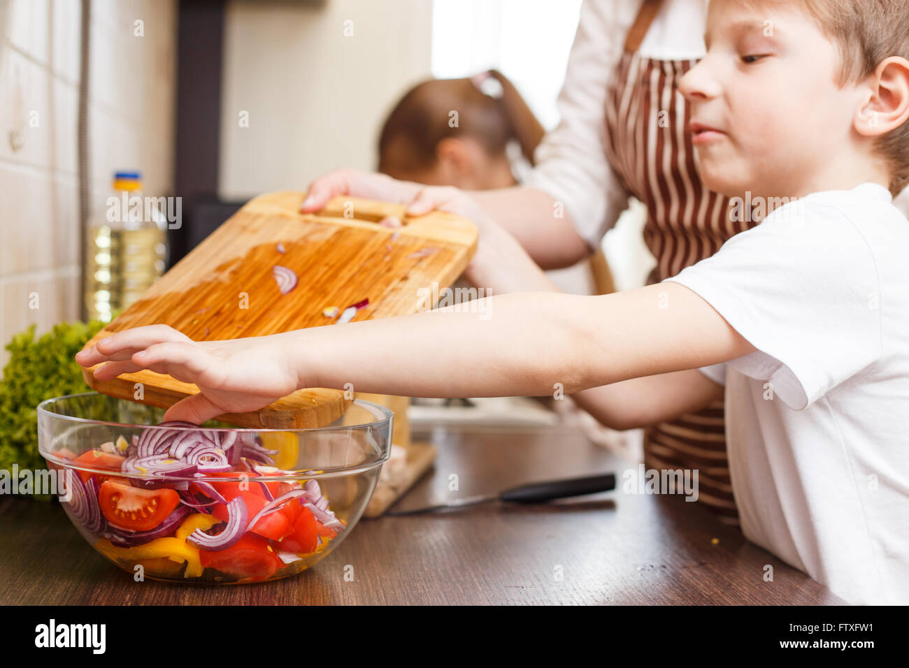 Family cooking background. Small boy help his mother with mixing salad ...