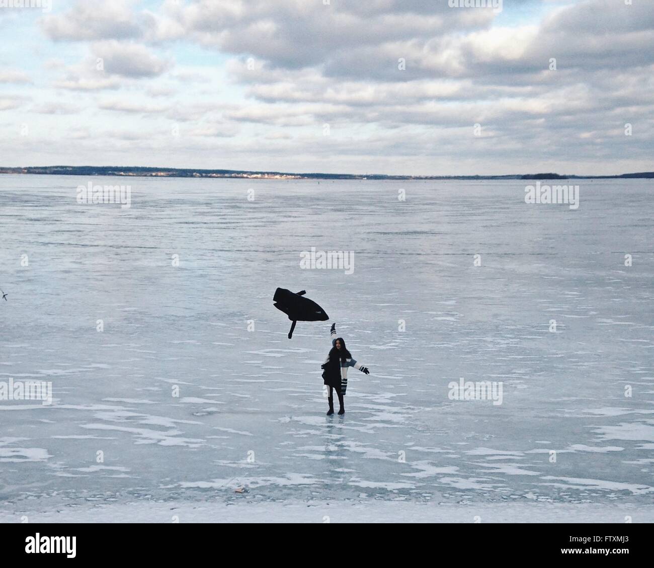 Woman standing on frozen sea throwing coat in the air Stock Photo - Alamy