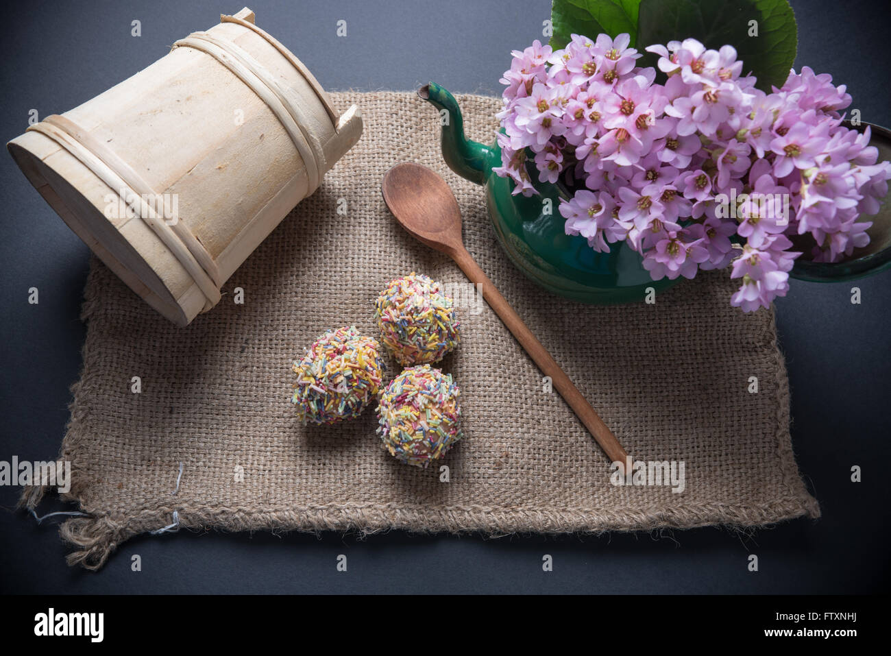 Easter eggs covered in sprinkles, teapot with flowers and wooden jug ...