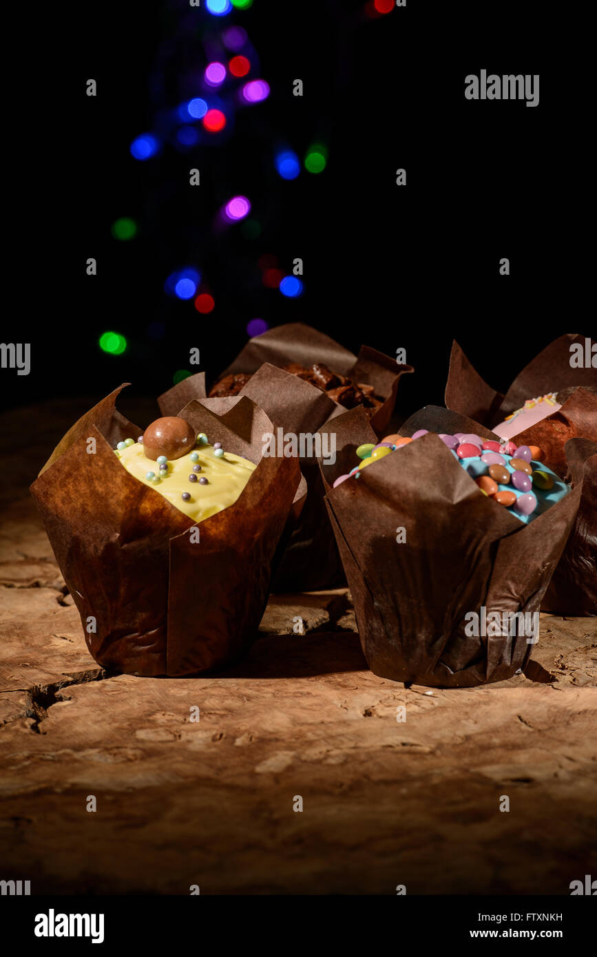 Four chocolate muffins decorated with icing and multi coloured sweets ...