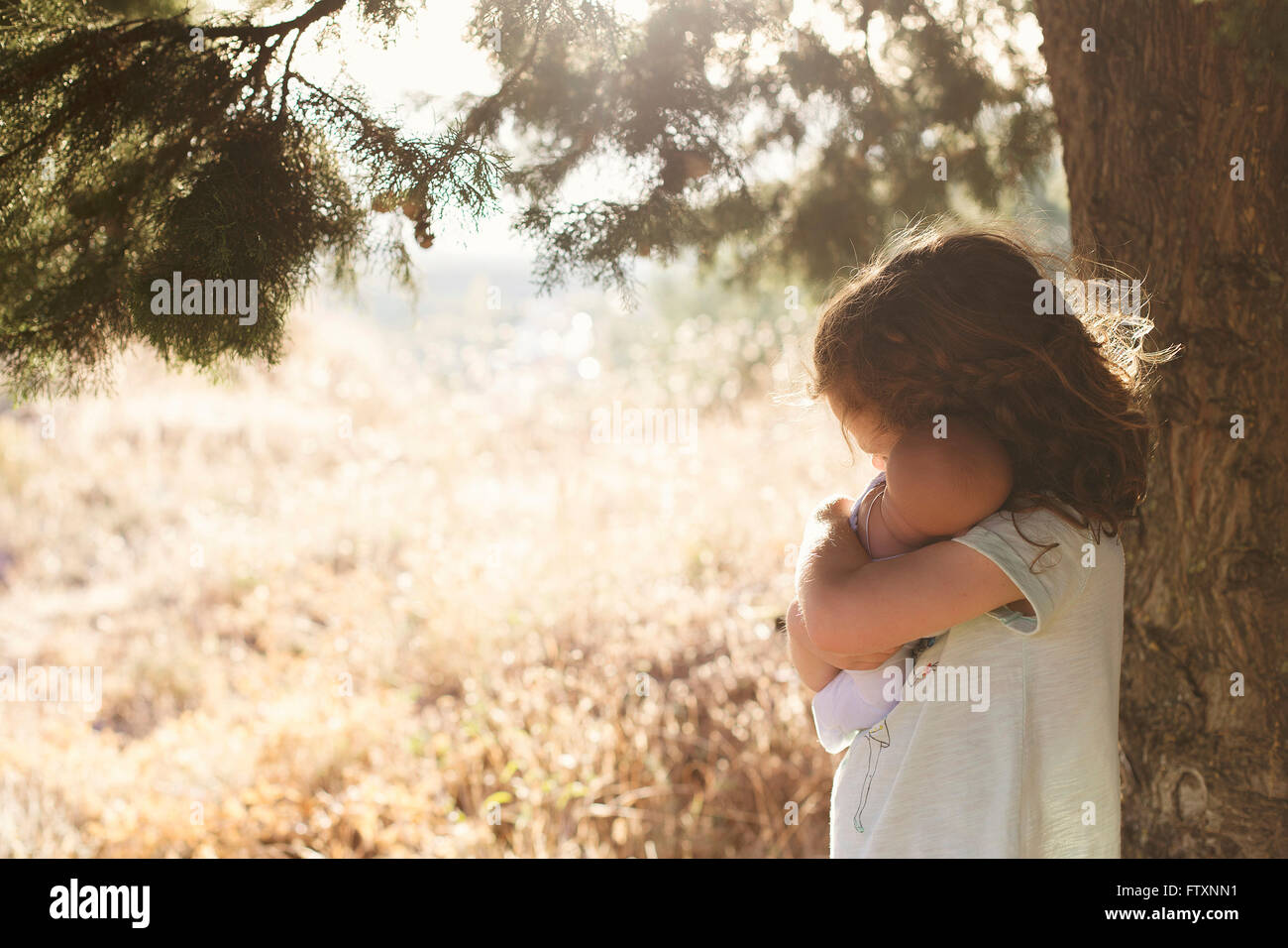 Side view of a girl in countryside hugging a doll, Granada, Andalucia ...