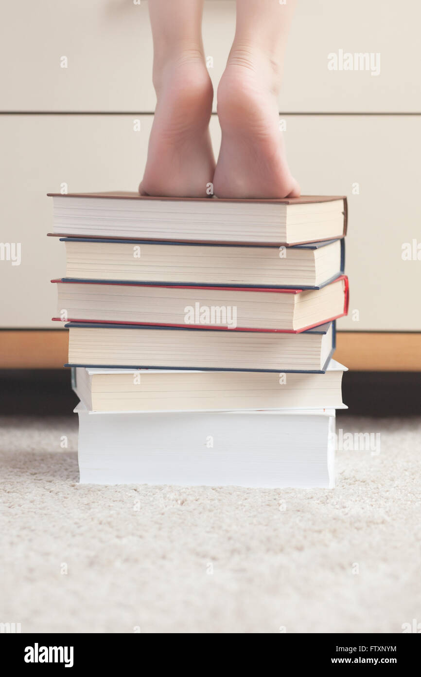 Girl standing on a stack of books Stock Photo - Alamy