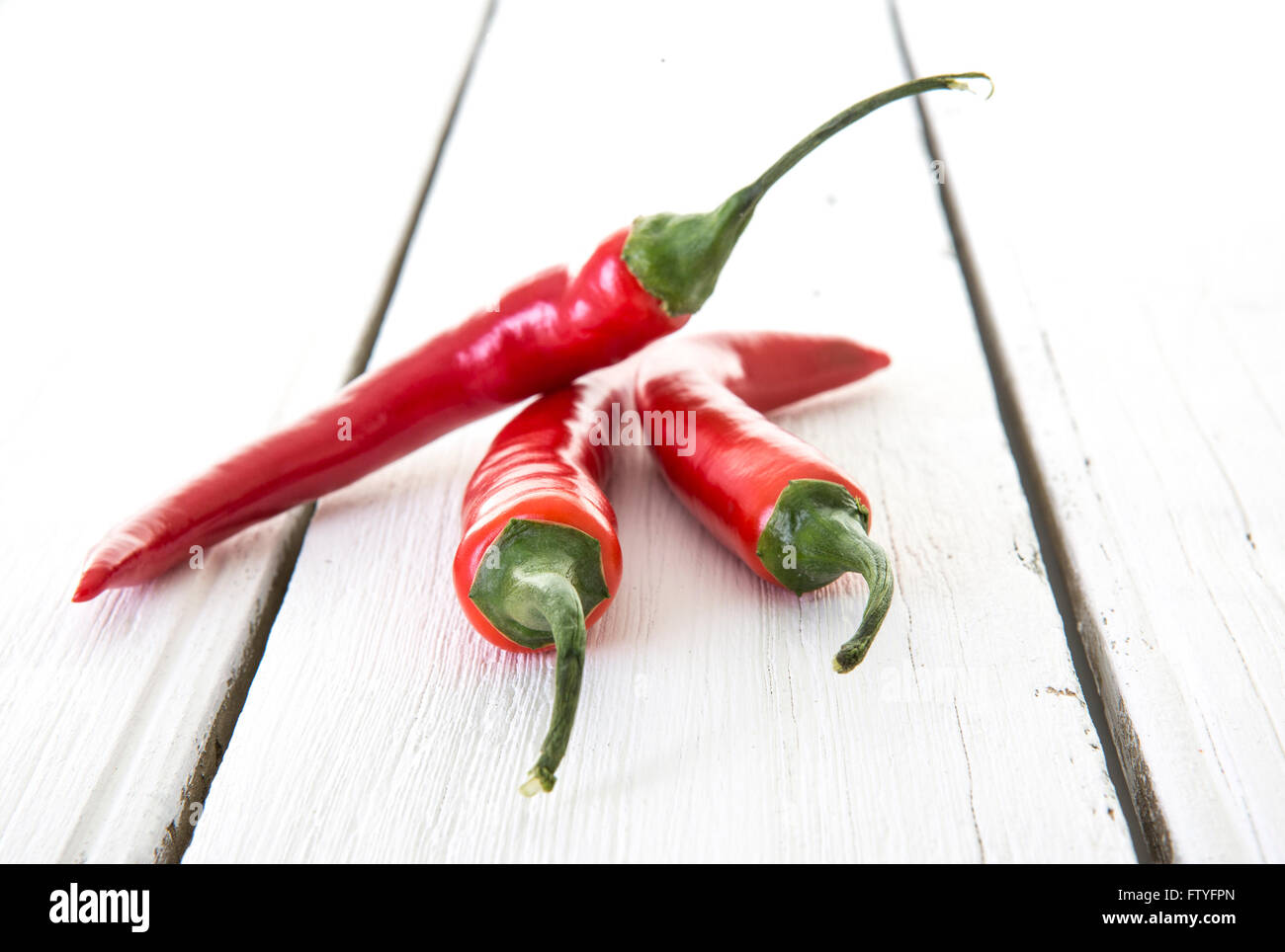 Three Red chili peppers on a rustic white wooden background Stock Photo ...