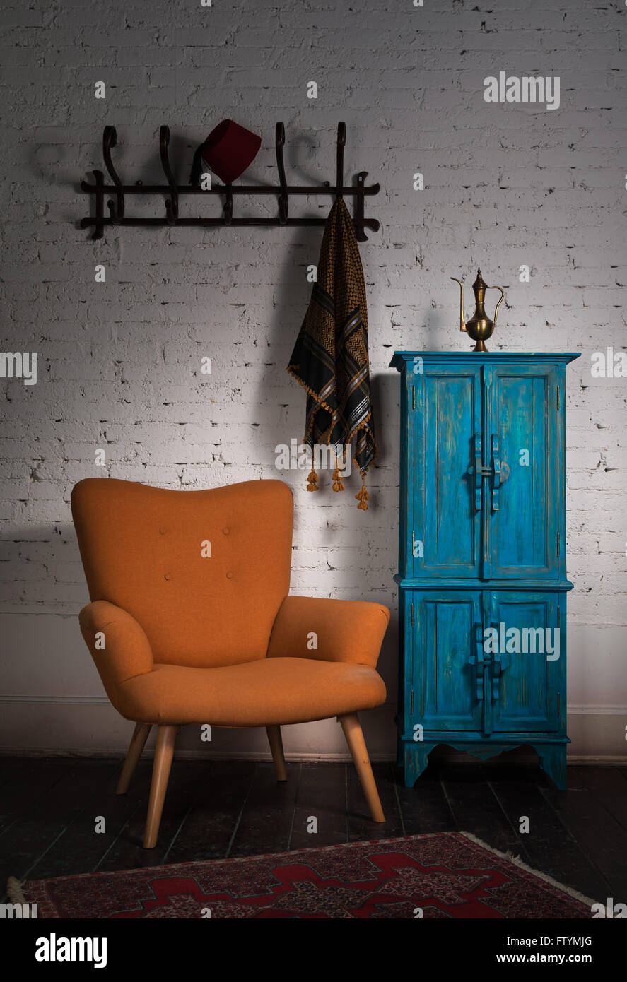 Composition of vintage orange armchair, blue cupboard, wall hanger with ...