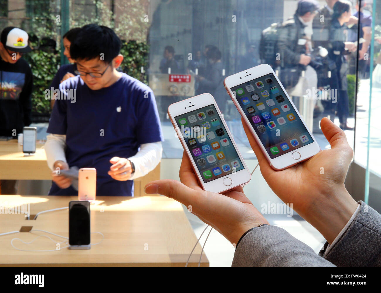 Tokyo, Japan. 31st Mar, 2016. A man compares sizes of the new iPhone SE ...