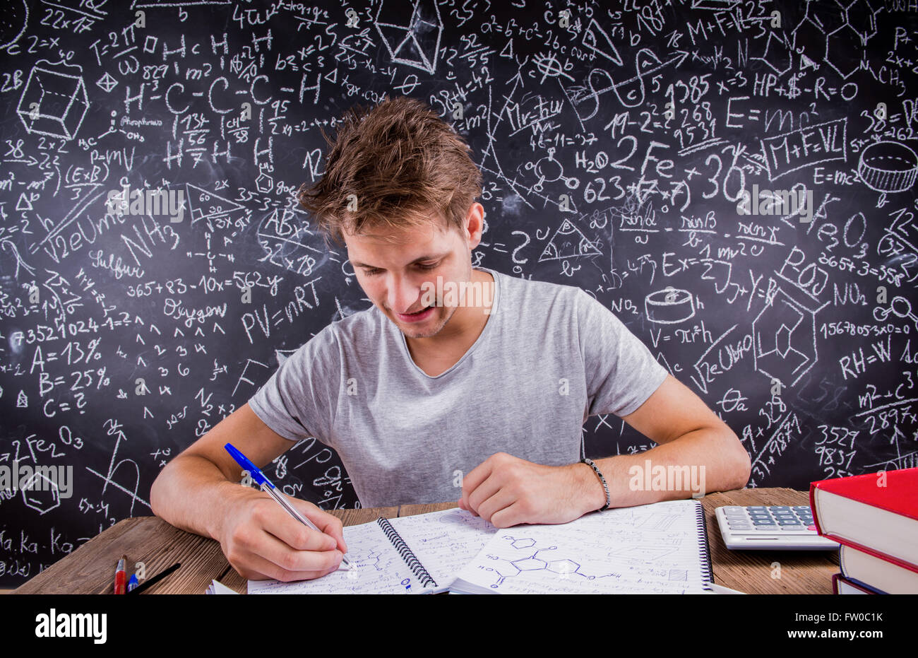 Hipster student doing his homework against a big blackboard Stock Photo ...