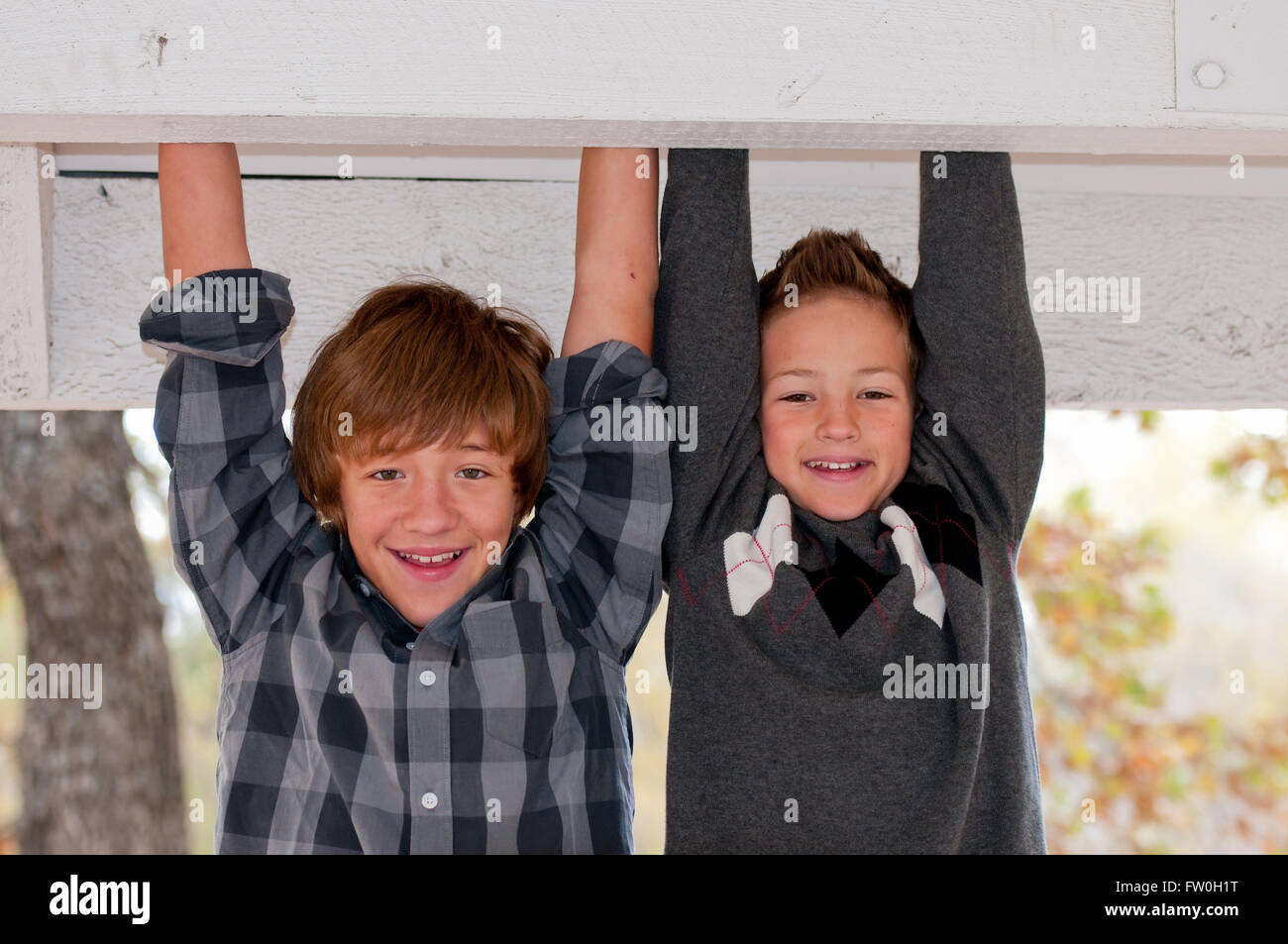 Portrait of two friends smiling and hanging from their arms at a park ...