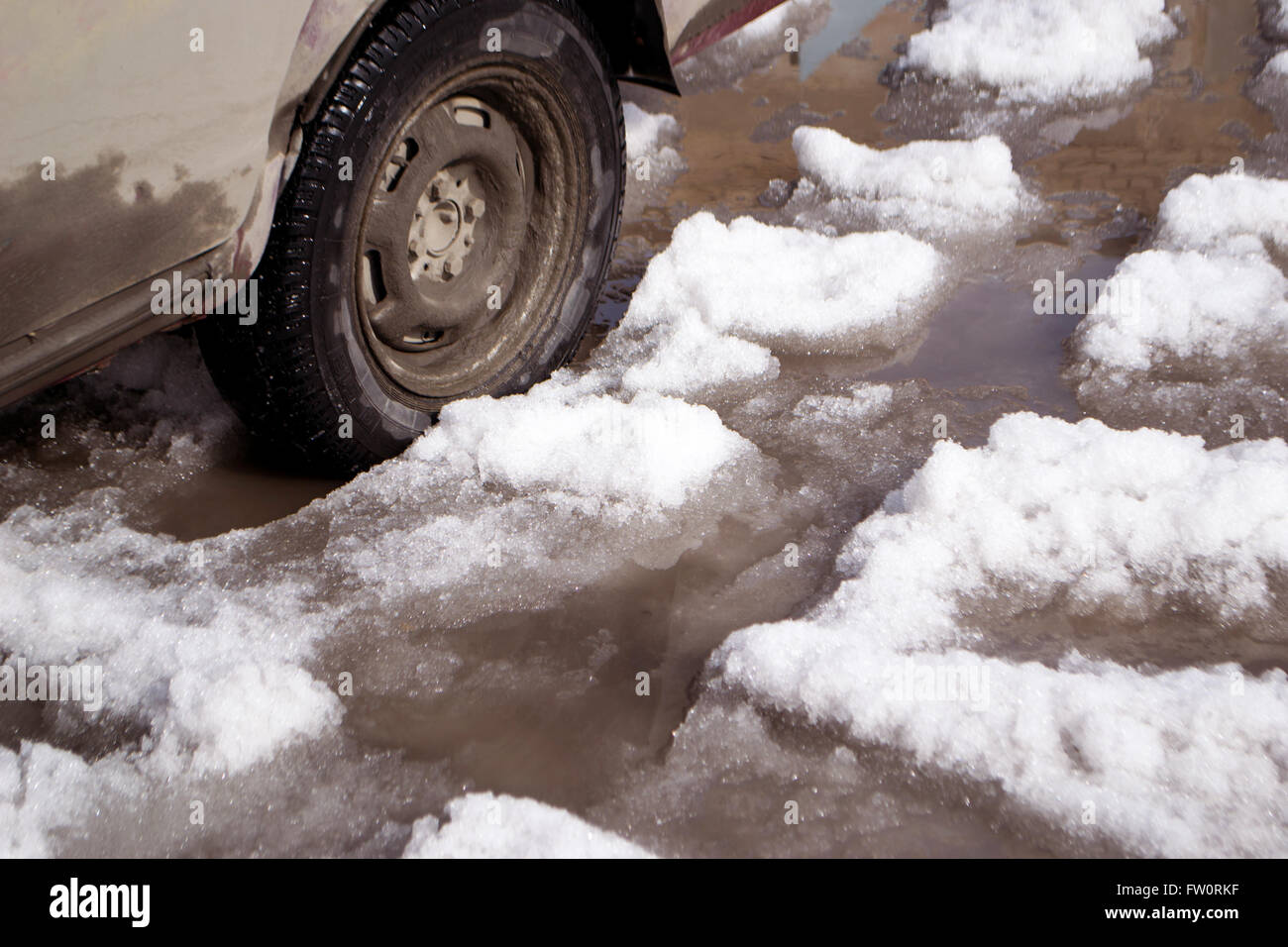 Melted snow flooded the road. Puddle closeup Stock Photo - Alamy