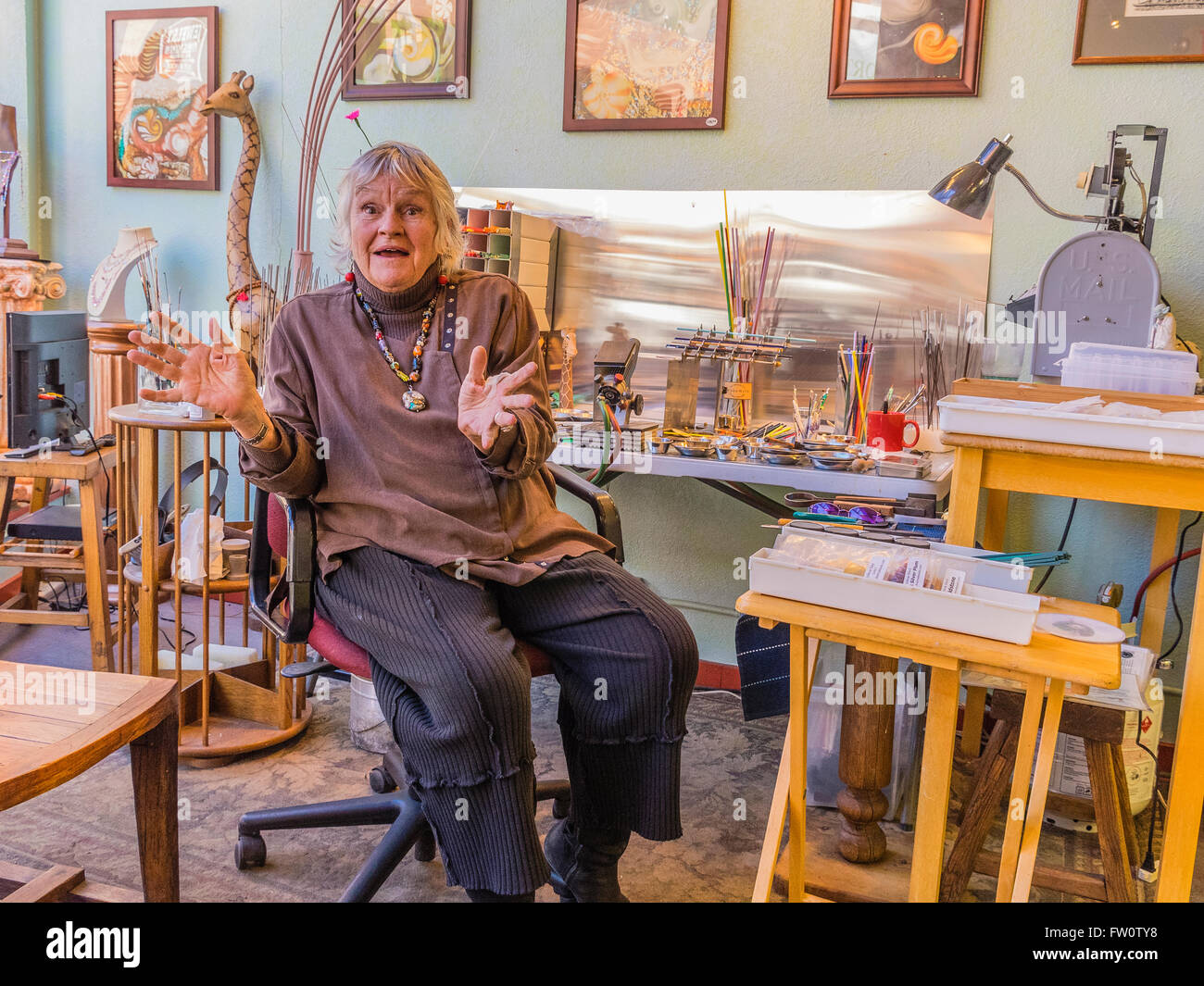 Kate Drew-Wilkinson glass artist sits at her work bench in her glass ...