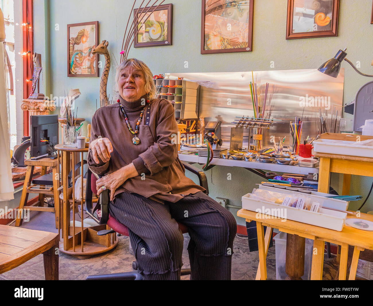 Kate Drew-Wilkinson glass artist sits at her work bench in her glass ...