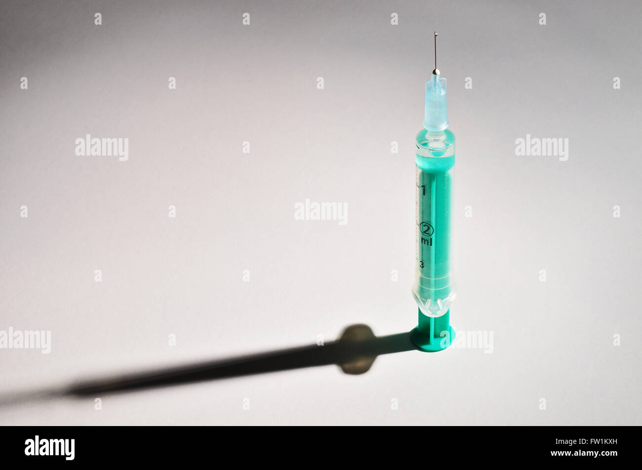 Syringe positioned vertically on a white background and casting shadow ...