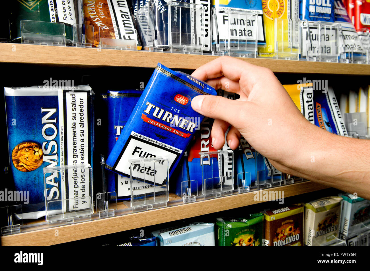 Hand removing a packet of Turner Hand Rolling Tobacco on sale in a ...
