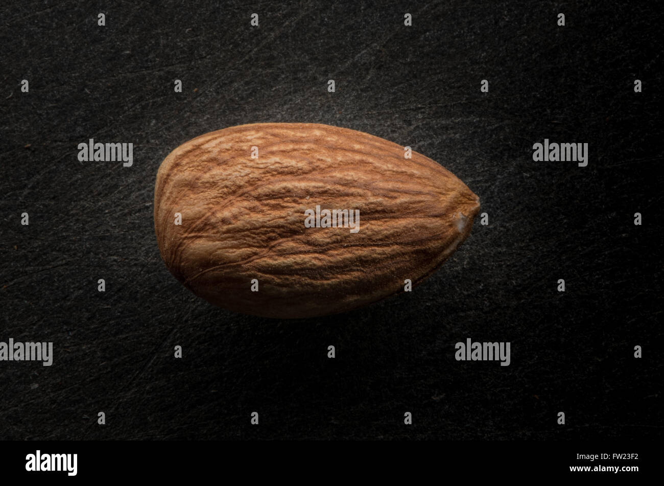 Single whole almond on black slate background Stock Photo - Alamy