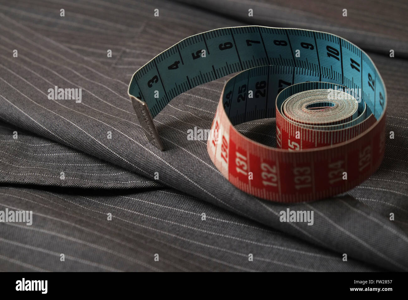 Measure tape being unrolled on top of a classic striped suit coat Stock ...