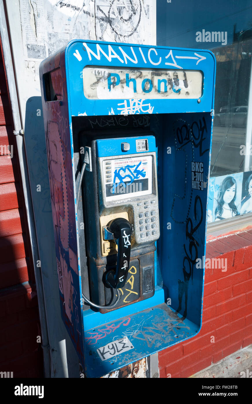 A vandalized and neglected public telephone booth covered with graffiti ...