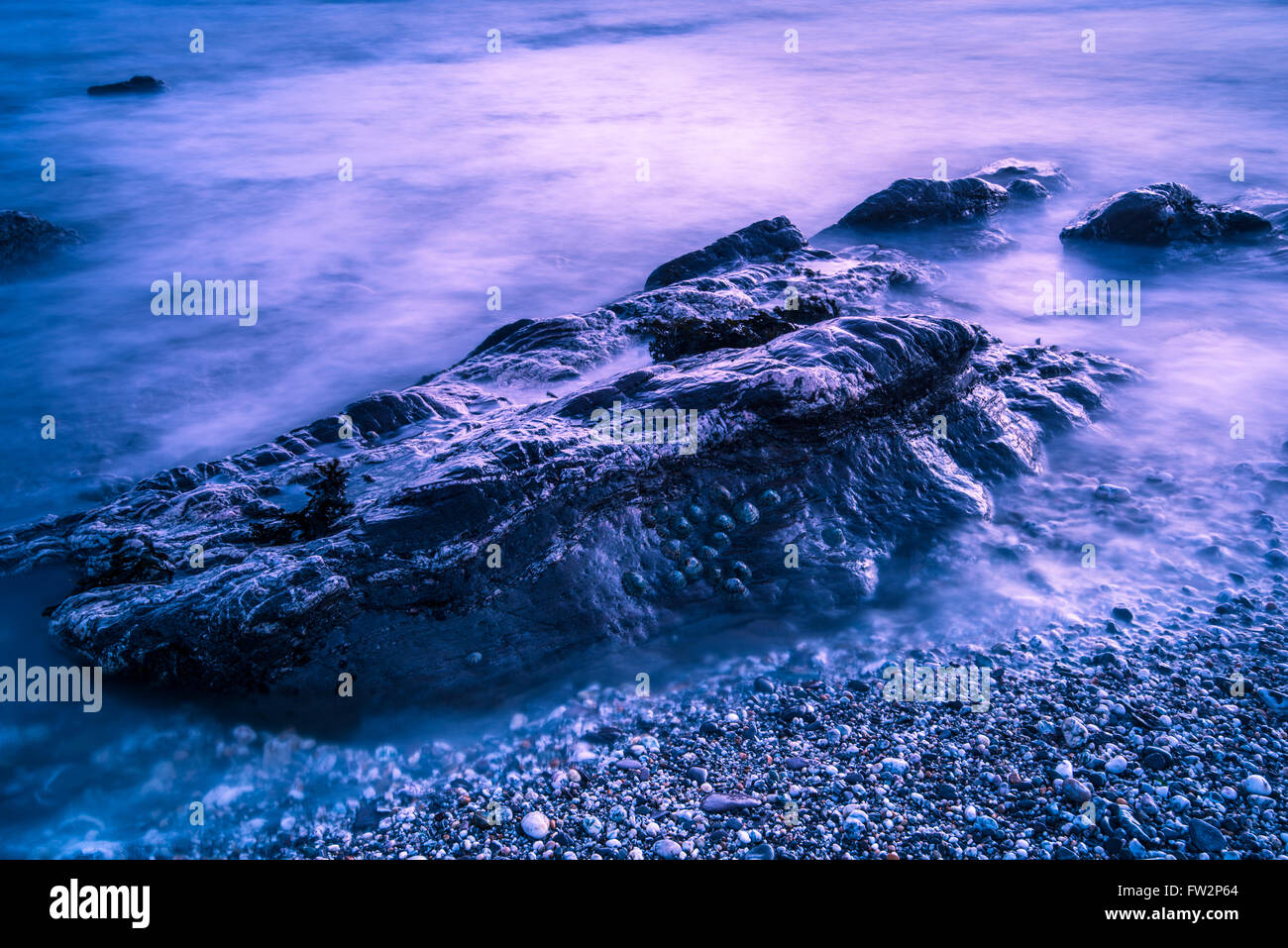 Slow motion waves on rocky beach at sunset Stock Photo - Alamy