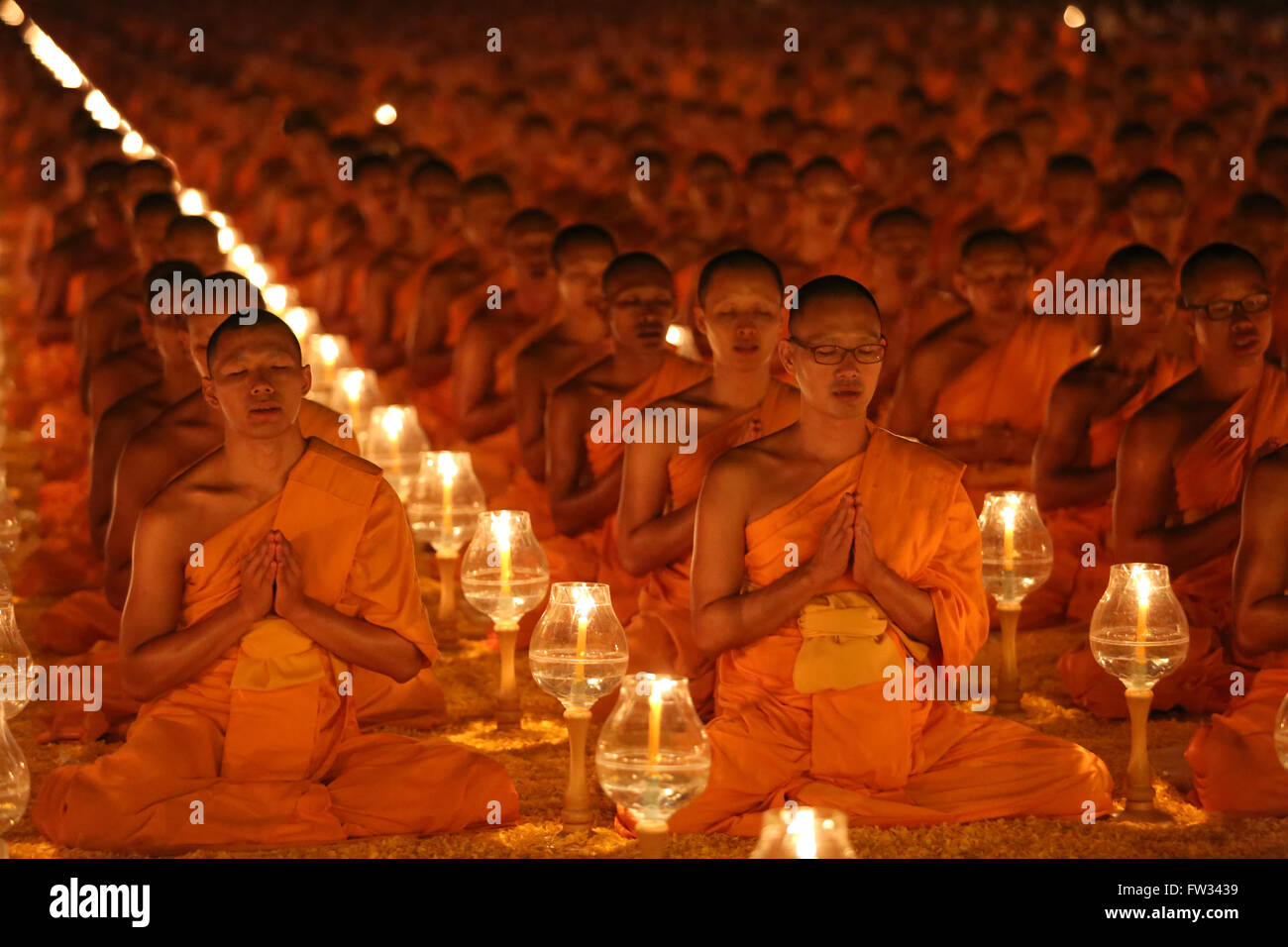 Monks sitting in rows praying and meditating by candlelight, Wat Phra ...