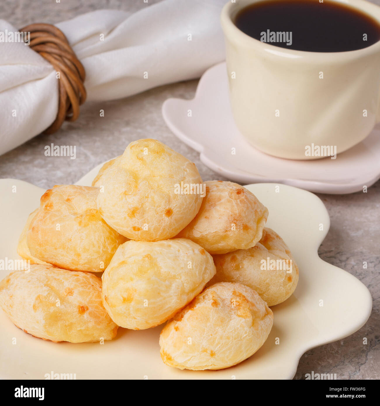 Brazilian snack pao de queijo (cheese bread) on white plate with cup of ...