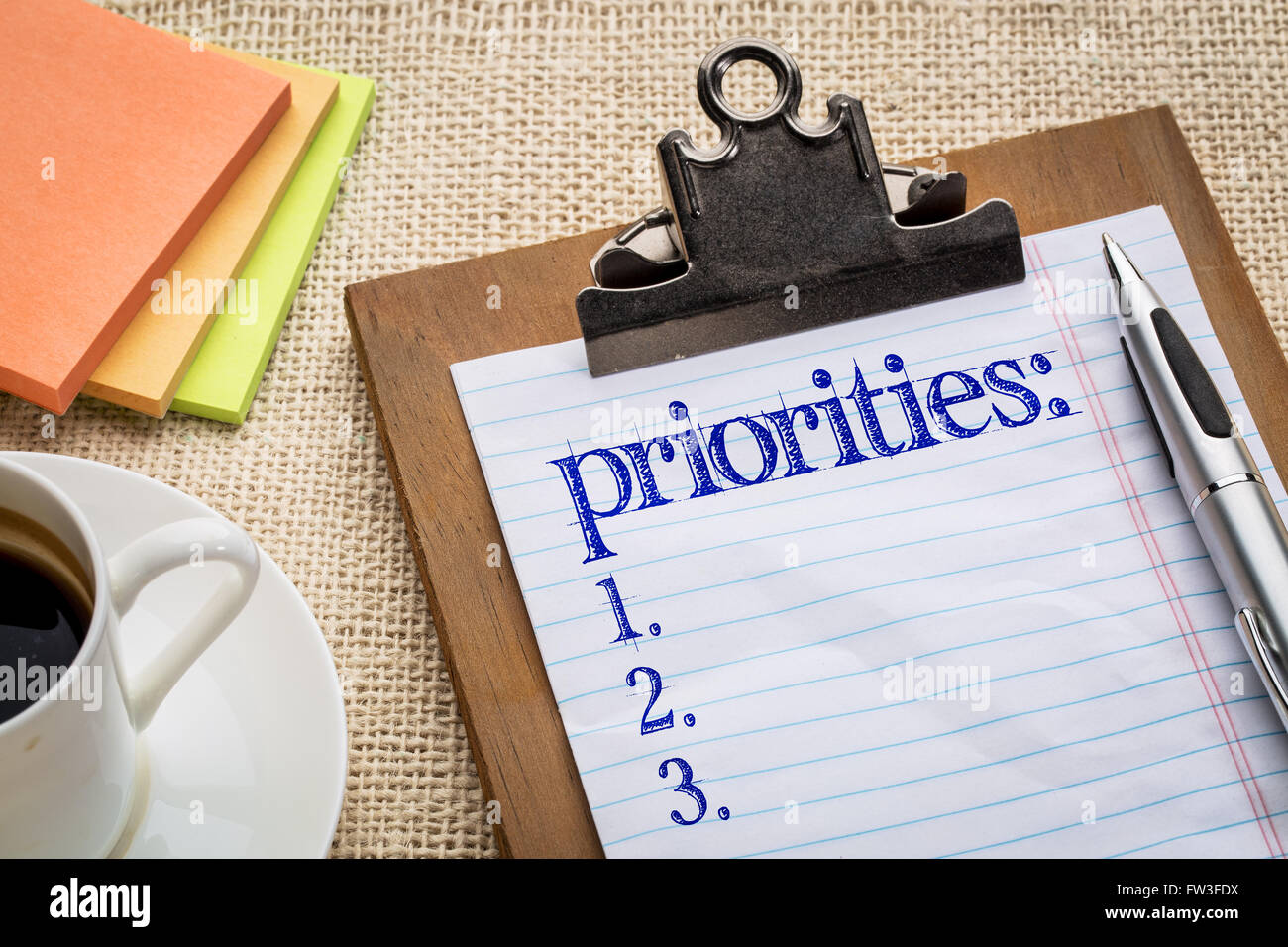 priorities list on clipboard with a pen, coffee and sticky notes ...