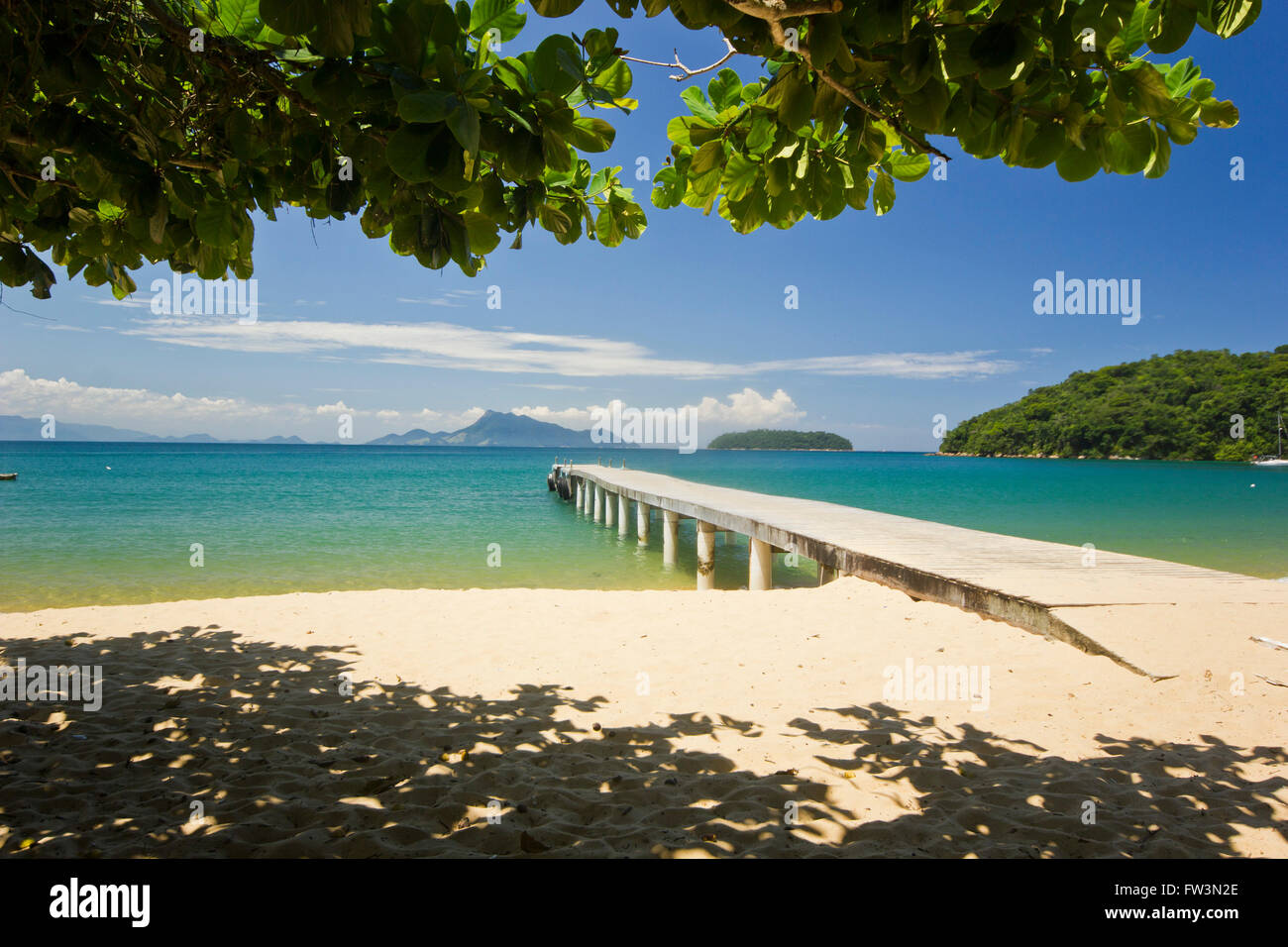 beautiful pier in ocean beach with deep green water, yellow sand and ...