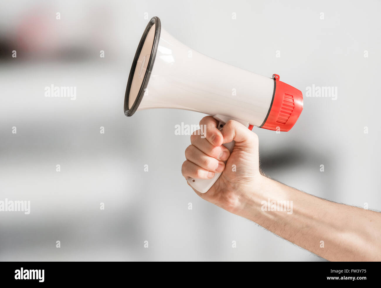 Hand holding a megaphone in an office building Stock Photo - Alamy