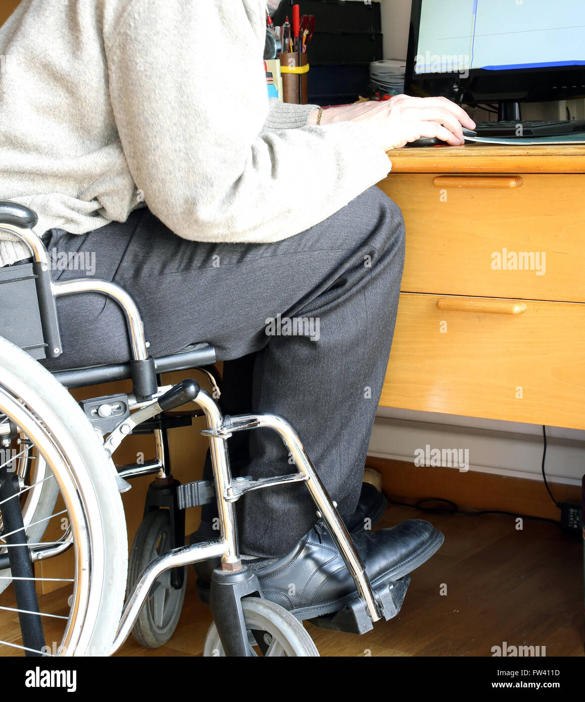 person sitting in a wheelchair at a desk with mouse and computer Stock ...