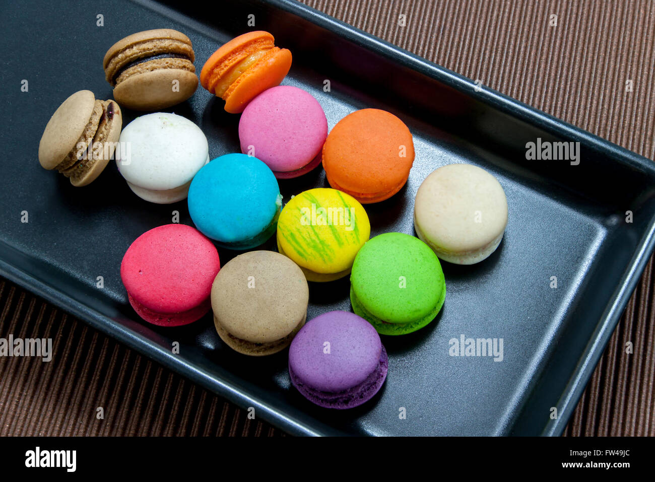 colorful macaroons in black ceramic plate on brown paper Stock Photo ...